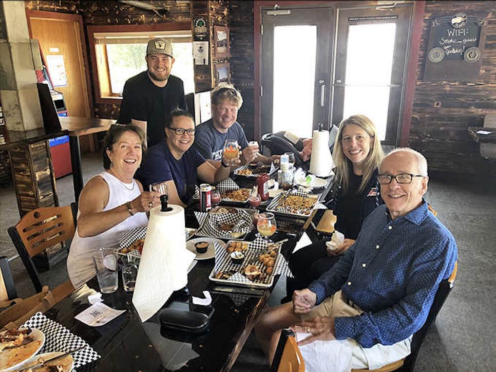 Happy diners caught in that magical moment between anticipation and satisfaction, forks poised above plates of barbecue perfection.