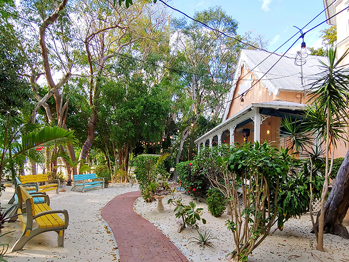 A coral-colored cottage nestled among tropical foliage, with cheerful benches creating an island welcome that whispers, "Slow down, you've arrived."