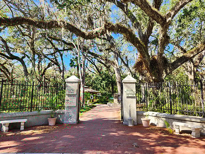 The grand entrance to Dunlawton Sugar Mill Gardens welcomes visitors with stately pillars and brick pathways, promising historical treasures and prehistoric surprises beyond.