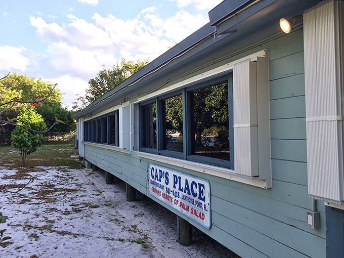Exterior: A seafoam-green wooden building perched on island shores, Cap's Place stands defiantly against time, its weathered charm whispering secrets of Prohibition days.
