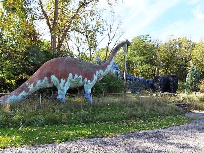 A faded brontosaurus stands sentinel at Prehistoric Forest, its weathered paint telling stories of decades gone by.
