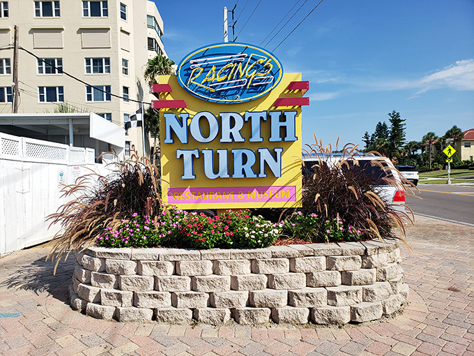 Racing's North Turn sign stands proudly against the Florida sky, a colorful beacon promising both motorsports nostalgia and oceanfront dining excellence.