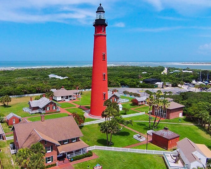 The iconic red tower of Ponce Inlet Lighthouse stands tall against the Florida sky, a crimson sentinel watching over the Atlantic coastline.