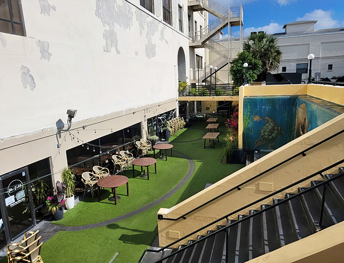 A hidden oasis awaits below street level, where artificial turf and sea turtle murals create DeLand's most unexpected dining courtyard.