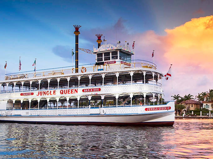 The majestic Jungle Queen riverboat glows in golden sunset light, its classic paddlewheel and ornate white railings promising an evening of old Florida charm.