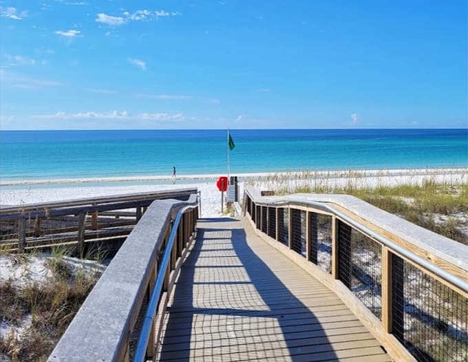 A wooden boardwalk leads to sugar-white sand and emerald waters that define the Emerald Coast perfectly.