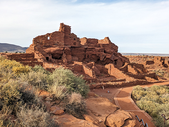 Ancient pueblo ruins stand against a backdrop of distant mountains. Wupatki National Monument preserves the homes of people who thrived in this challenging landscape.