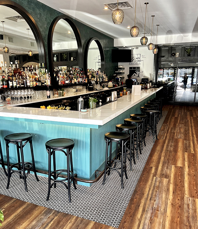 Bottles stand at attention behind a turquoise bar where mixologists craft cocktails with the same precision as the pasta makers in the kitchen.