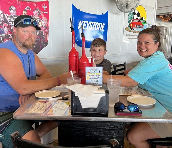 Happy diners enjoy the authentic racing atmosphere, surrounded by memorabilia while creating their own memories over shared meals and laughter.