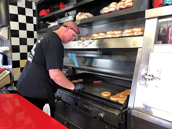 Behind the grill, culinary choreography unfolds as buns toast to golden perfection and patties sizzle with practiced precision.