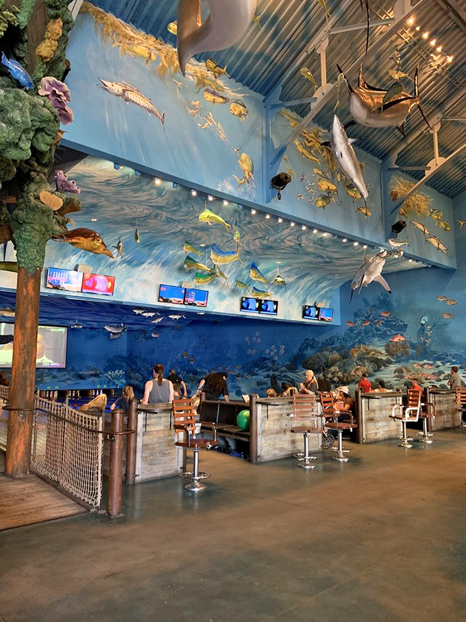 The ceiling becomes an upside-down aquarium where sharks and game fish appear suspended in mid-swim above diners and bowlers alike.