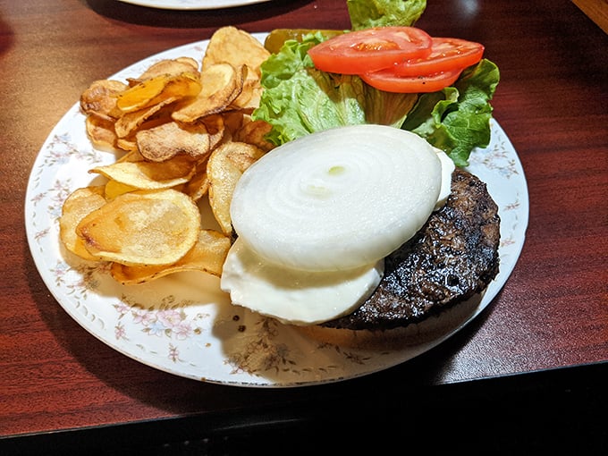 The restaurant's signature burger stands tall and proud, topped with a perfect onion slice and surrounded by crispy chips.