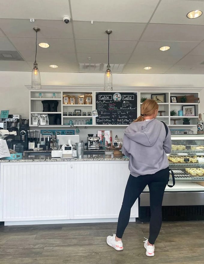 A customer contemplates the day's offerings at the clean, white-paneled counter topped with gleaming display cases.