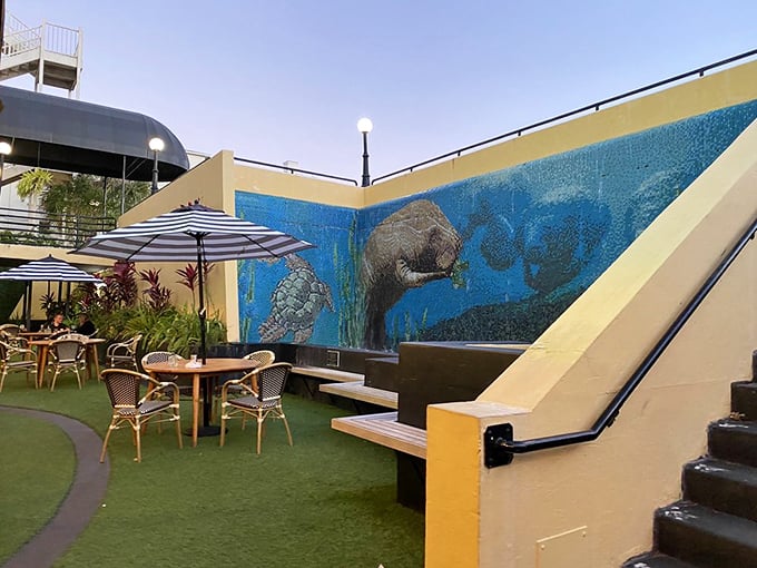 The outdoor courtyard offers a secret garden experience &ndash; striped umbrellas and artificial turf creating an oasis beneath a manatee mural's watchful gaze.