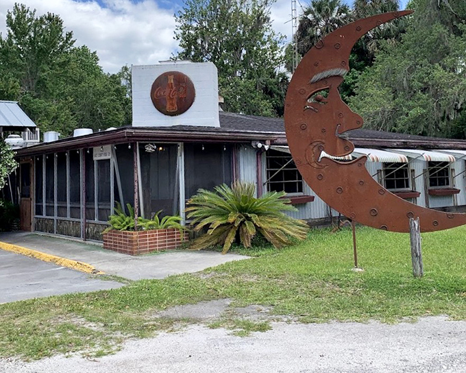 A whimsical moon sculpture guards The Yearling Restaurant's entrance, hinting at the quirky character waiting inside this beloved local seafood spot.