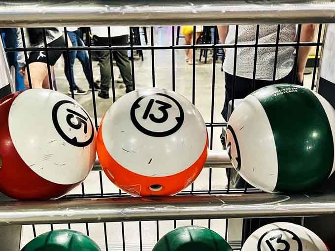 Classic bowling balls rest in their rack, each one a potential strike waiting to happen or a gutter ball in disguise.