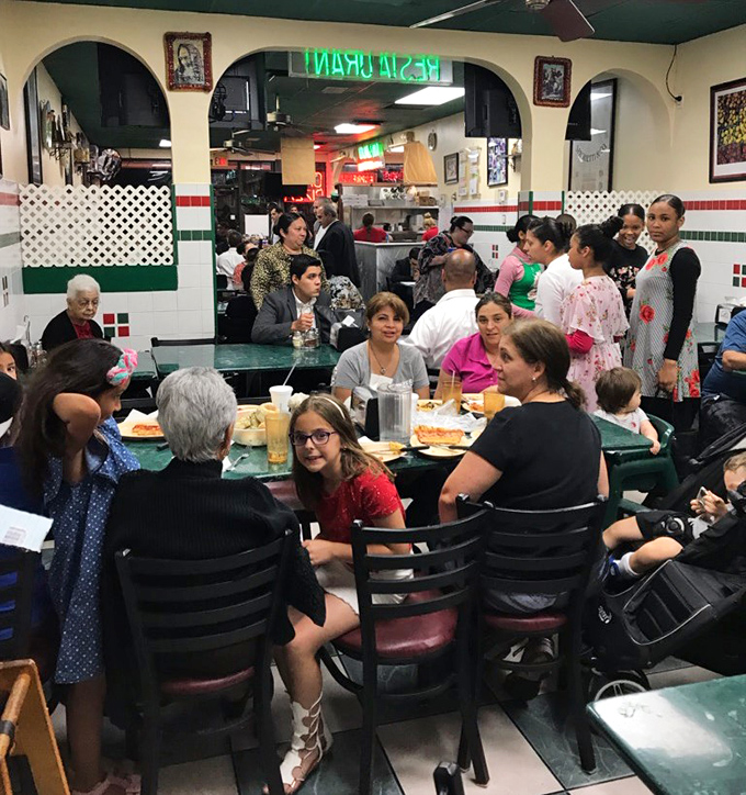 A bustling snapshot of community&mdash;families and friends gathered around tables, creating memories one bite at a time.
