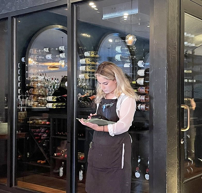 Behind the wine display, expertise awaits. This is someone who can guide you to the perfect Barolo pairing without a hint of wine snobbery.