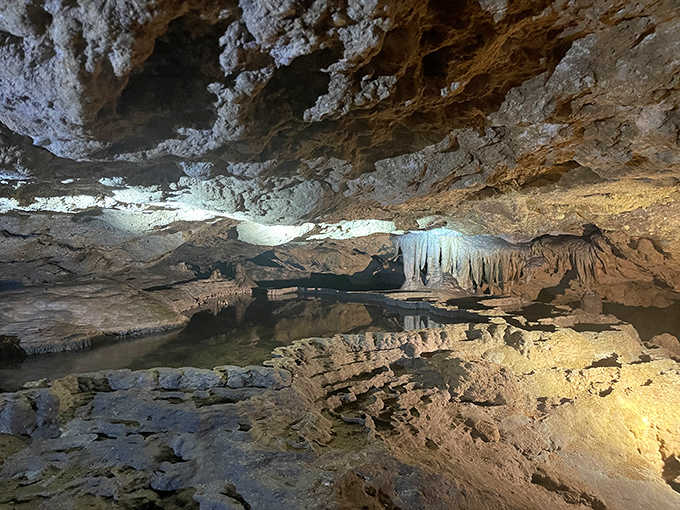 Still waters perfectly mirror the cave ceiling, creating an illusion that doubles the majesty of these ancient formations.