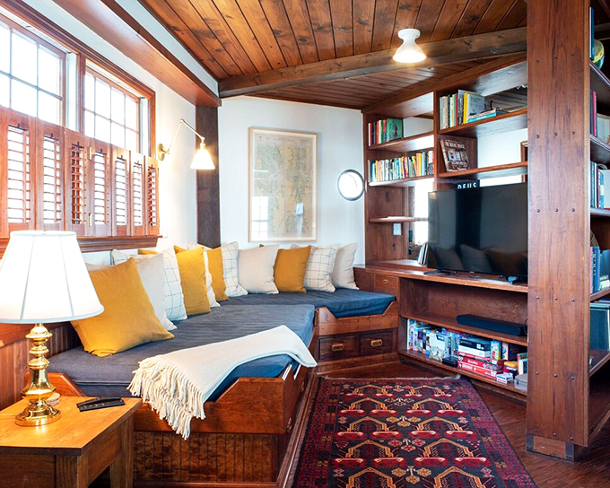 The cozy reading nook combines comfort and function, with built-in storage beneath cushions and shelves lined with books for rainy days.