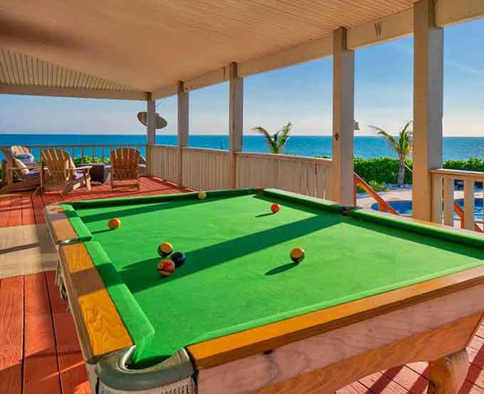 A pool table on a covered porch overlooking the ocean proves that some people understand luxury isn't about fancy, it's about fun with a view.