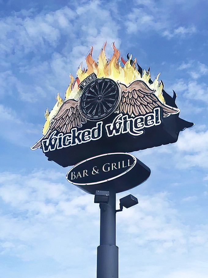 The dramatic Wicked Wheel sign serves as a beacon for hungry travelers, its distinctive design instantly recognizable against the Panama City Beach skyline.
