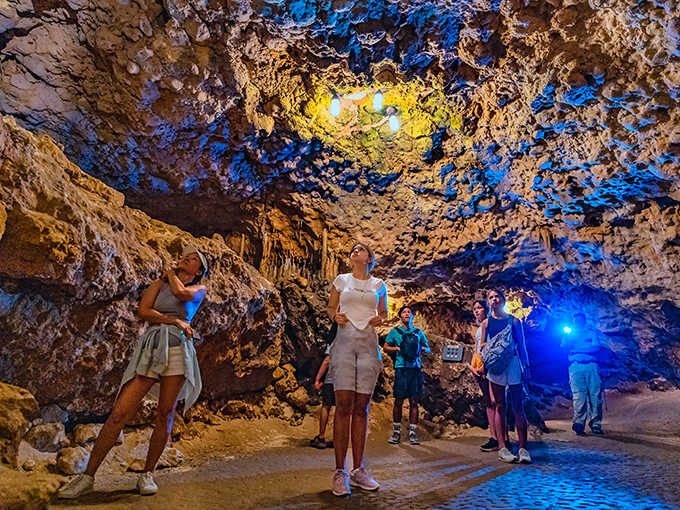 Visitors gaze upward in wonder as colorful lighting accentuates the textured ceiling, each bump and crevice telling a geological story.