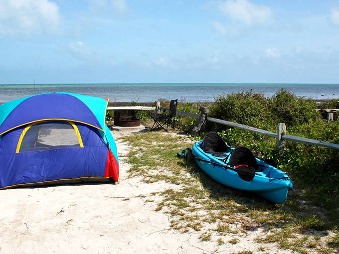 A colorful tent pitched on white sand at Long Key State Park, with a turquoise kayak ready for adventure on crystal-clear waters.