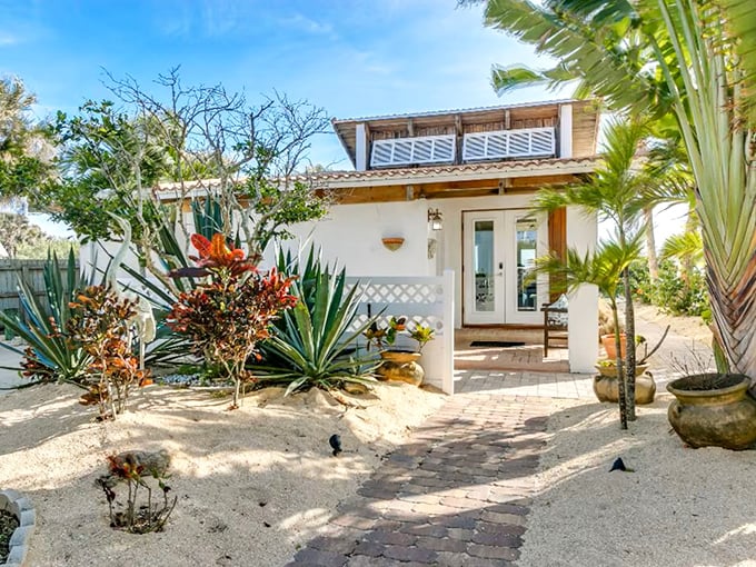 Beach cottage perfection with tropical landscaping that says "Welcome to your temporary slice of paradise."
