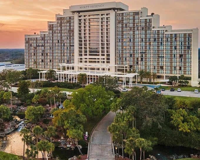The Hyatt Regency Grand Cypress stands majestically against an orange Florida sunset, promising adventures beyond its impressive fa&ccedil;ade.
