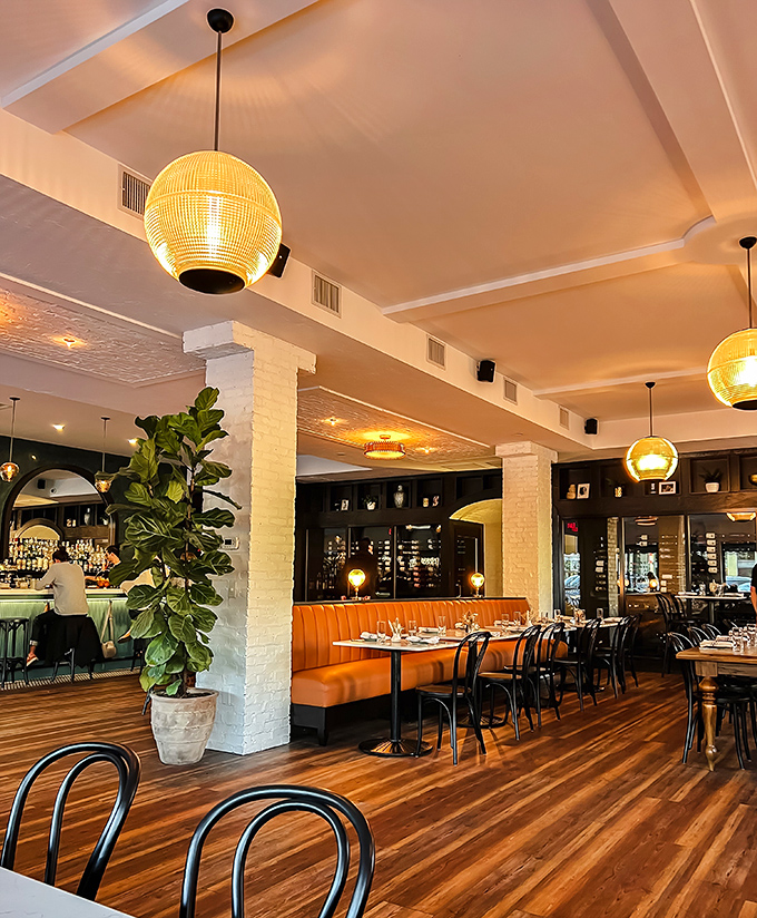 Warm wooden floors meet caramel leather booths under golden globe lights, creating that rare sweet spot between "special occasion" and "Tuesday night pasta craving."