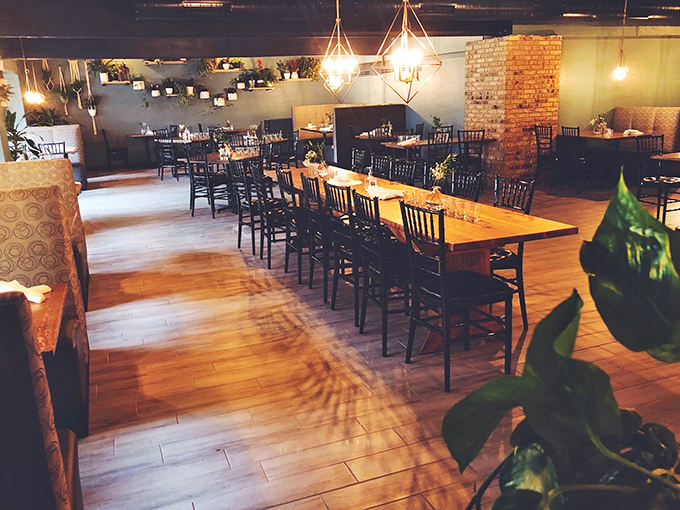 Warm wooden tables bathed in geometric lighting create the perfect atmosphere for lingering conversations and memorable meals.