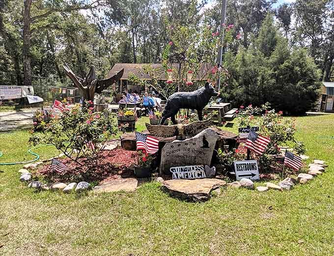 A striking wolf silhouette stands proudly atop stones, surrounded by American flags and colorful flowers – a patriotic tribute to these native predators.