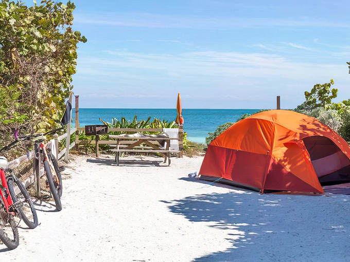 An orange tent nestled on Grayton Beach's pristine white sand, with the emerald Gulf waters visible just steps away.
