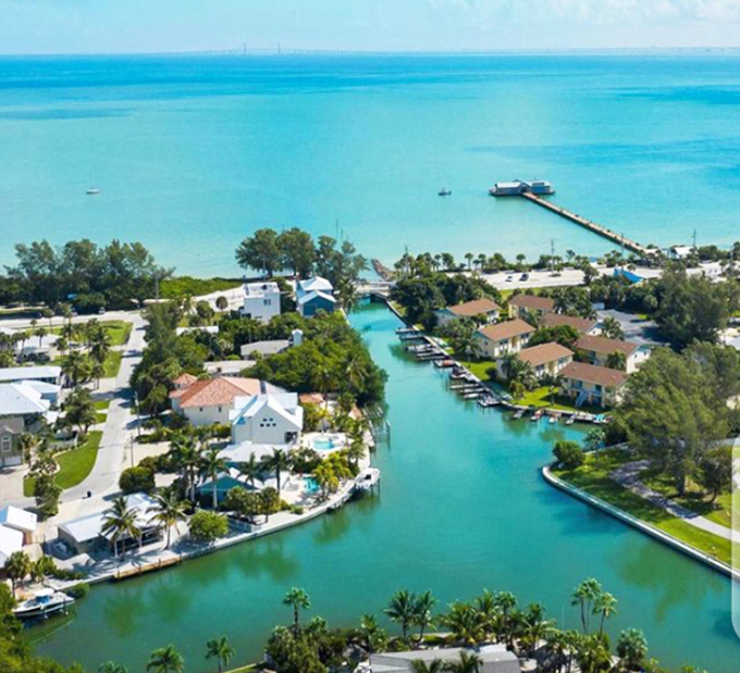 Anna Maria Island's waterways carve through paradise, where turquoise channels lead boats home between waterfront homes basking in sunshine.