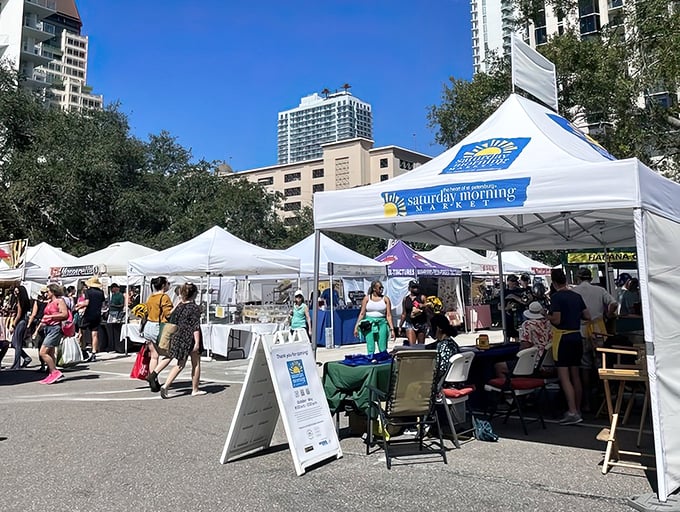 Shoppers stroll between vendor booths at the Saturday Morning Market, where local produce, artisan goods, and prepared foods create a weekly festival atmosphere.