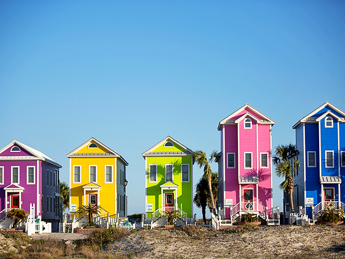 Colorful beach houses line the shore at St. George Island, their vibrant hues creating a cheerful contrast against the white sand dunes.