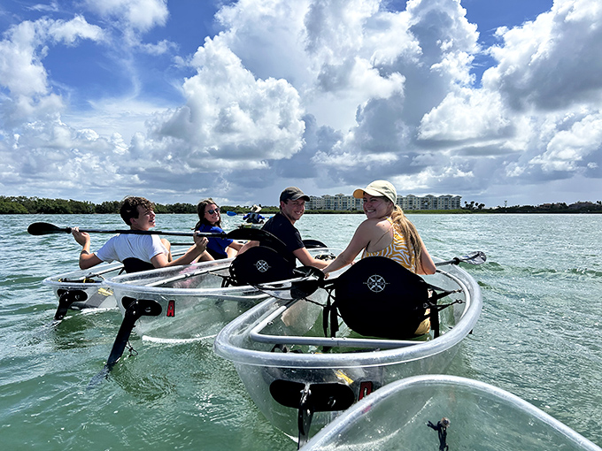 Aquatic social hour: Friends sharing the clear kayak experience create memories that last longer than any souvenir t-shirt ever could.