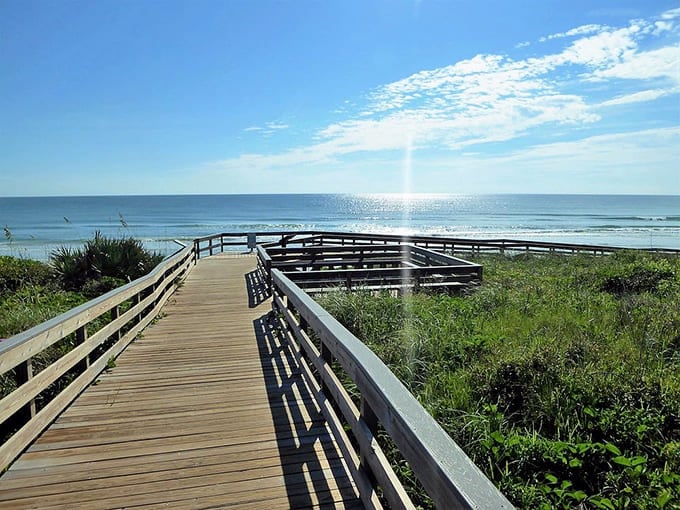 The boardwalk curves toward the ocean like an invitation, promising that perfect beach day where the only footprints are yours.
