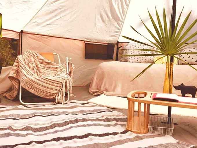 Cozy blankets and pillows turn this tent into a bedroom that would make any glamping fan smile with joy.