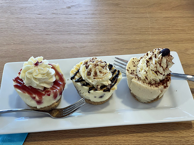 Three perfect miniature cheesecakes &ndash; each a different flavor &ndash; sitting pretty on a white plate, waiting to be devoured.