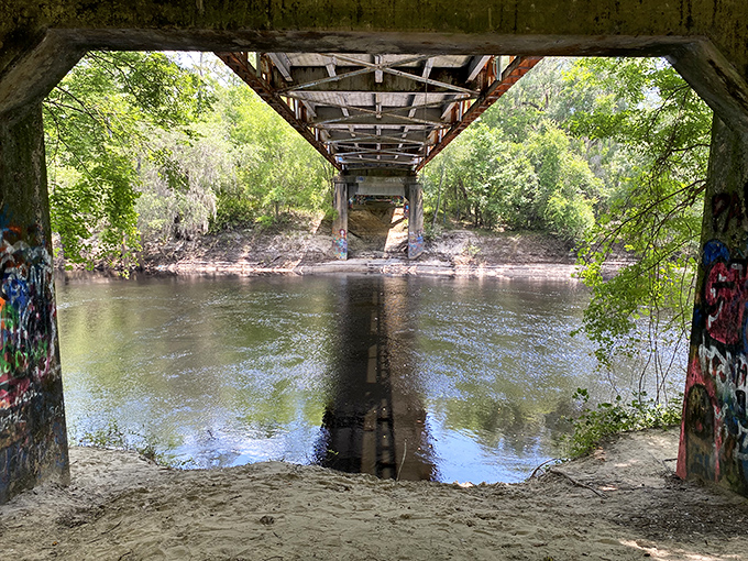 Beneath the bridge's weathered bones, the river creates a natural sanctuary where time seems to slow to the pace of the water.