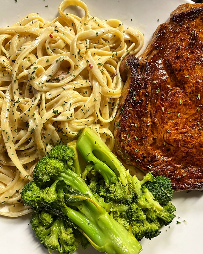 Pasta poetry on a plate! Al dente fettuccine glistens with rich sauce alongside a perfectly seared steak and vibrant broccoli &ndash; a symphony of flavors.