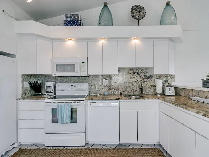 Gleaming white kitchen where vacation meals become events and morning coffee tastes like freedom.