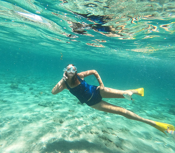Beneath the turquoise surface, snorkelers discover an underwater playground where visibility rivals Caribbean waters and colorful fish dart between coral formations.