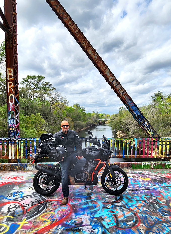 A visitor pauses mid-bridge, his motorcycle a modern contrast to this vintage crossing that's found new life as an artistic landmark.