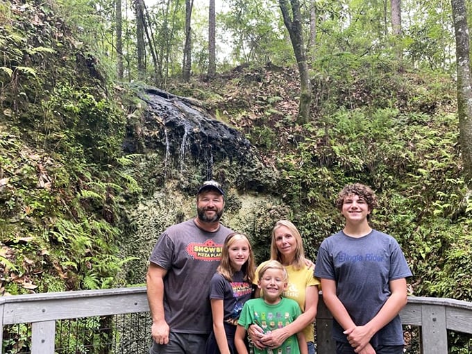 Families gather at the waterfall overlook, experiencing that rare moment when kids actually put down their phones for something more impressive.