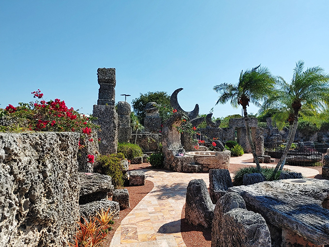 Coral Castle's mysterious stone garden features massive coral formations arranged in fascinating patterns, with flowering plants adding splashes of color to this enigmatic creation.