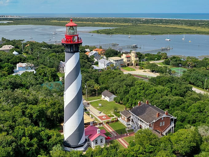 Panoramic views showcase St. Augustine's lighthouse surrounded by lush Florida greenery, with the Intracoastal Waterway stretching toward the Atlantic Ocean.