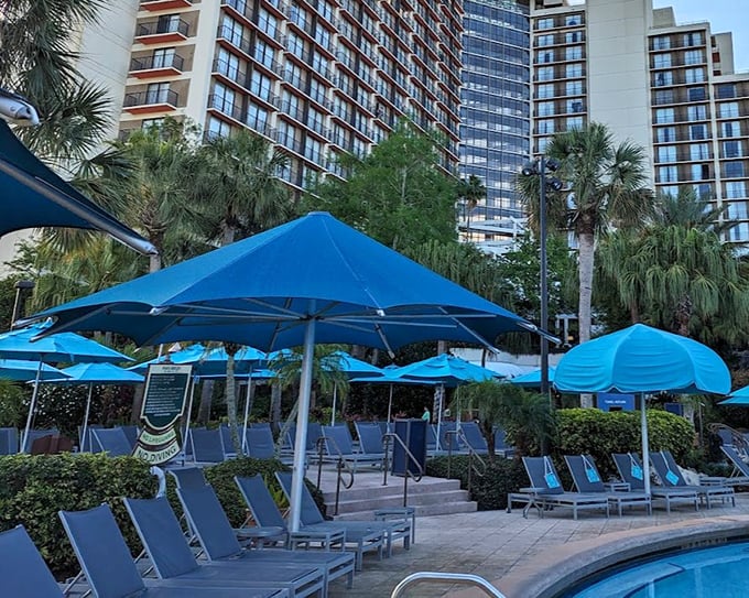 Blue umbrellas dot the poolside like tropical flowers, offering shady retreats between refreshing dips.